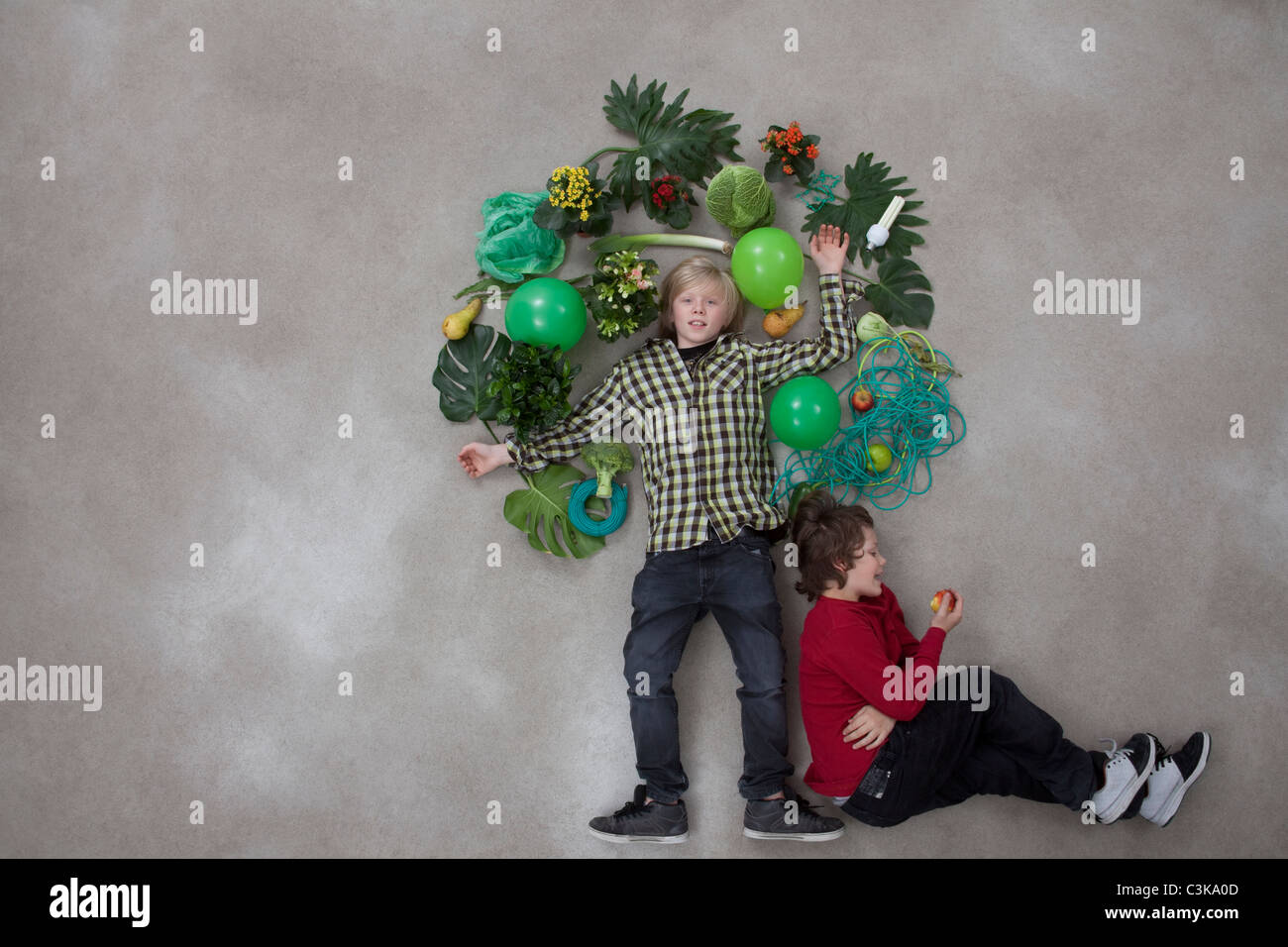 Boy forming tree shape and another boy sitting, eating fruit Stock ...