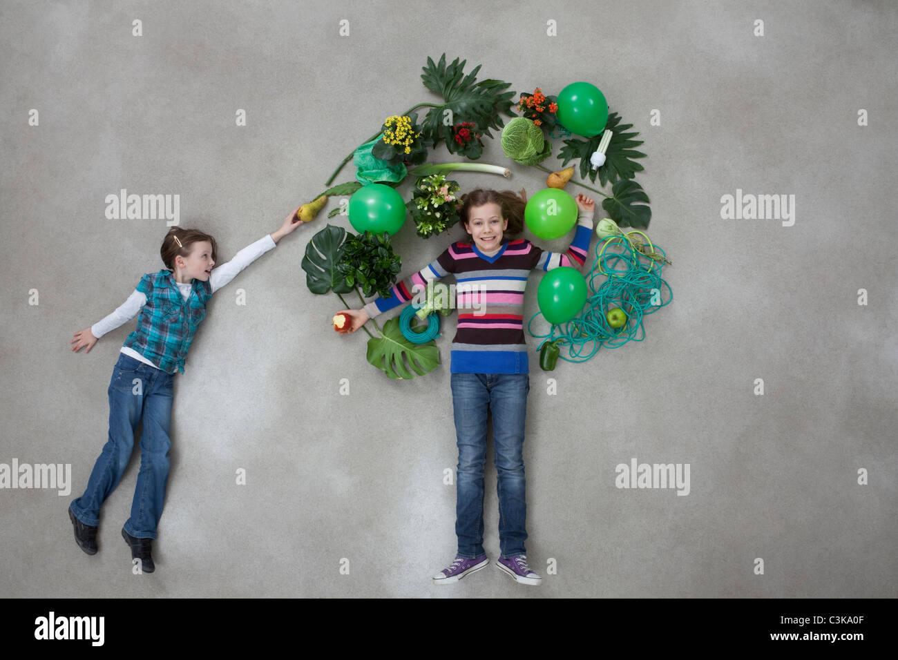 Girl forming tree shape, another girl holding fruit Stock Photo - Alamy