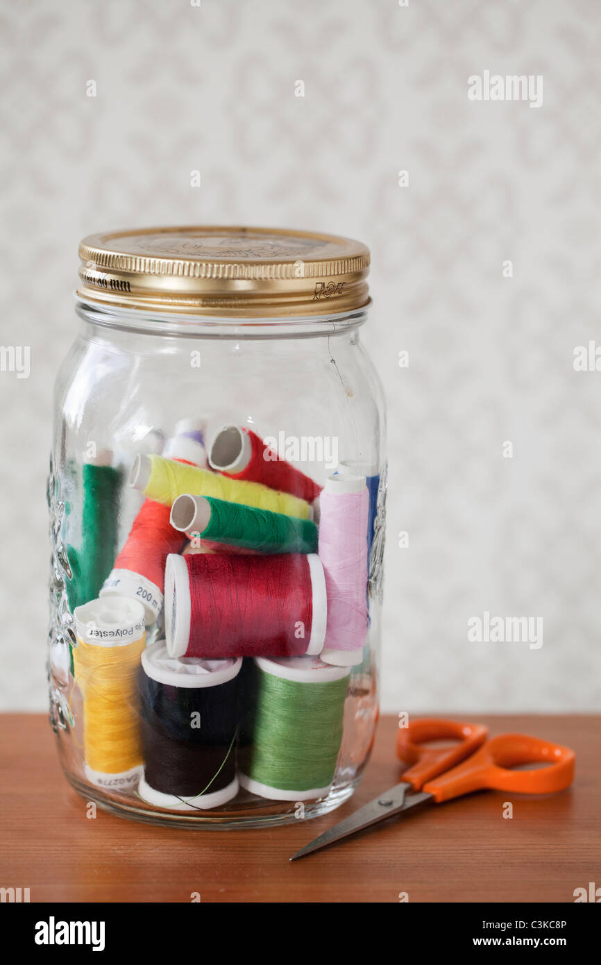 Spools of thread in jar with scissors Stock Photo - Alamy