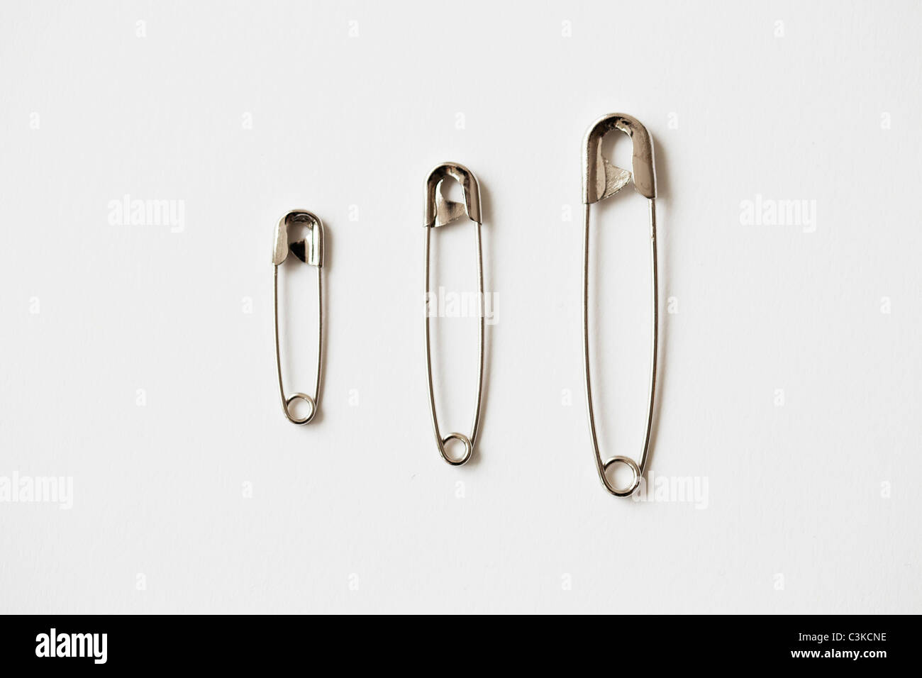 Three safety pin in a row, studio shot Stock Photo - Alamy