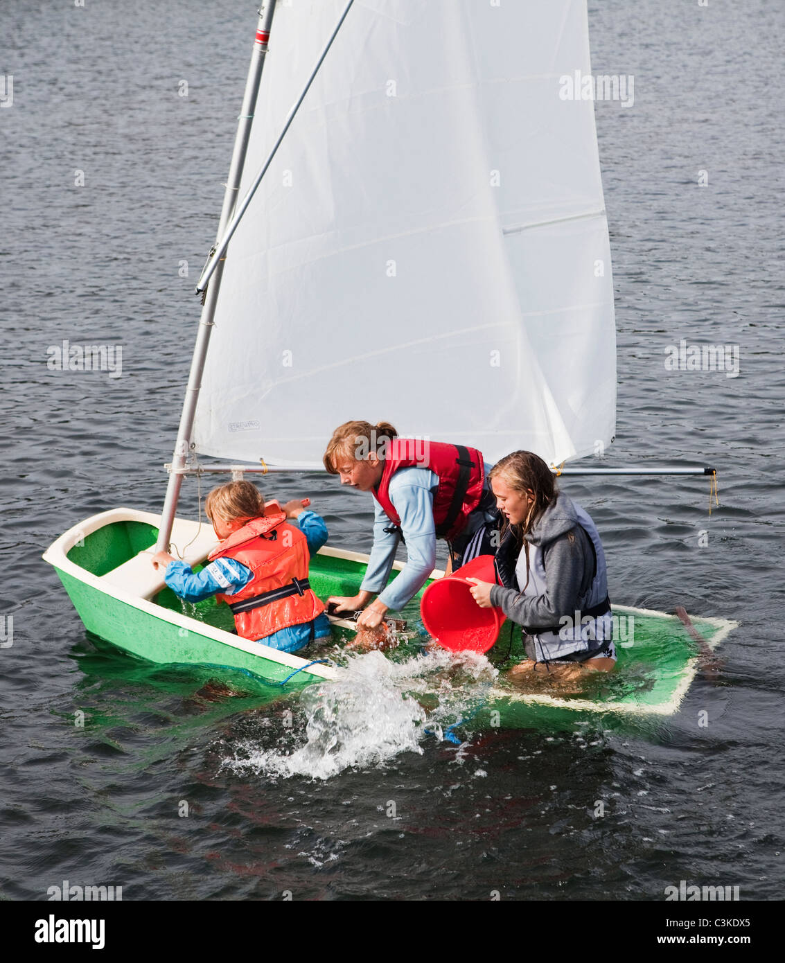 Three girls removing water from dinghy Stock Photo - Alamy