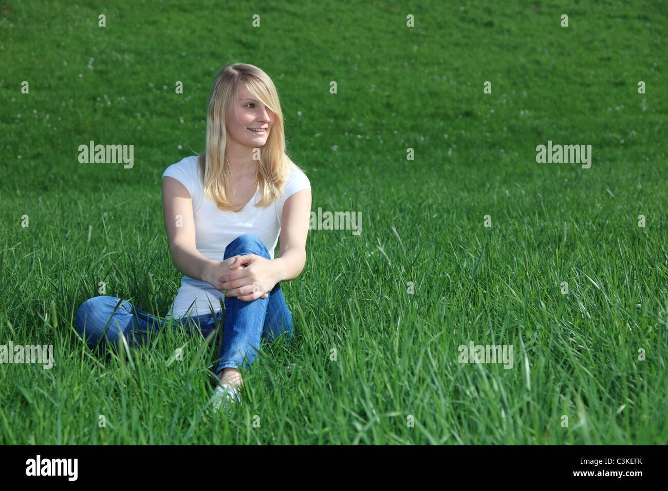Attractive young woman resting outside on green meadow Stock Photo - Alamy