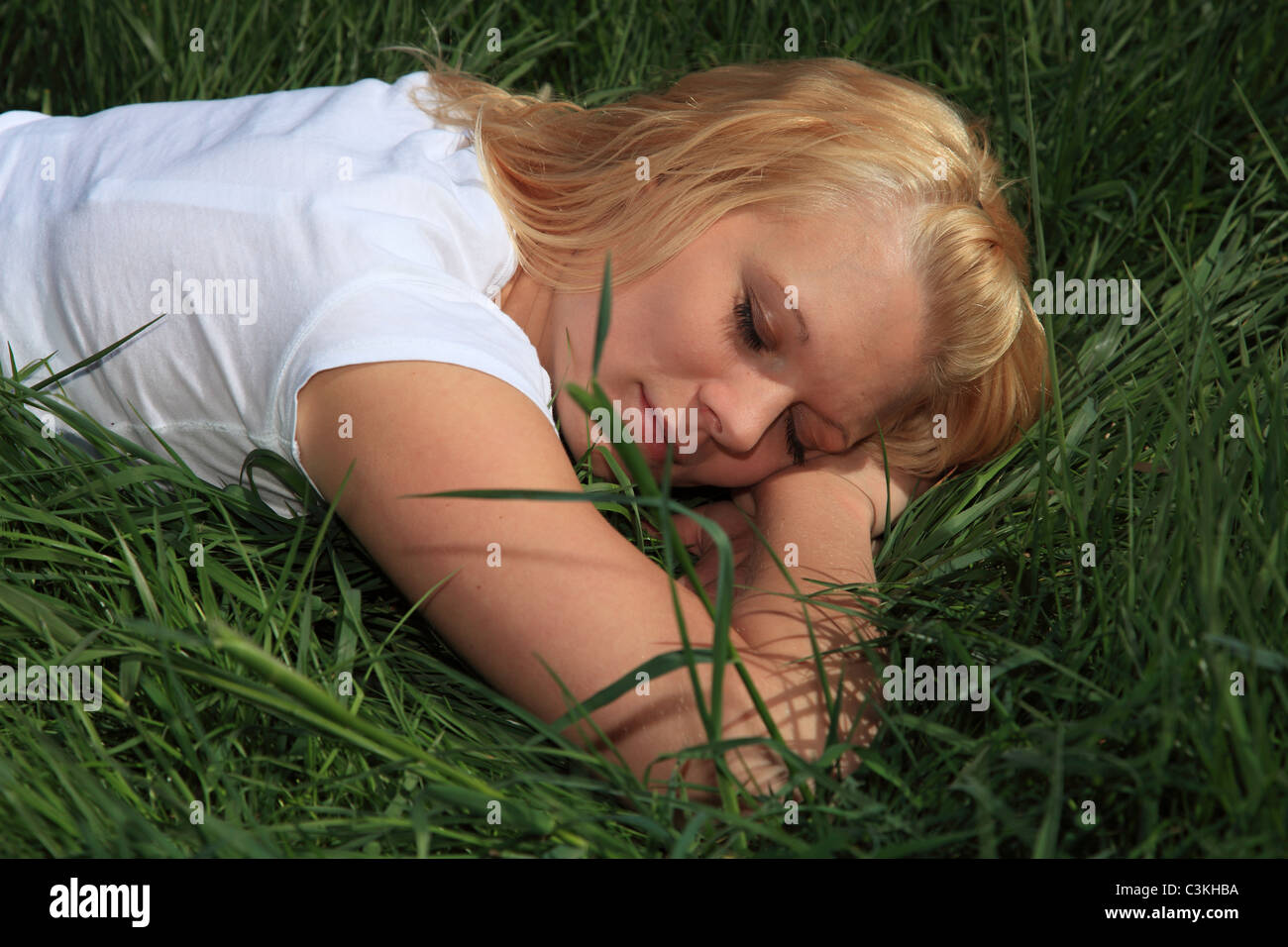 Attractive young woman resting outside on green meadow Stock Photo - Alamy