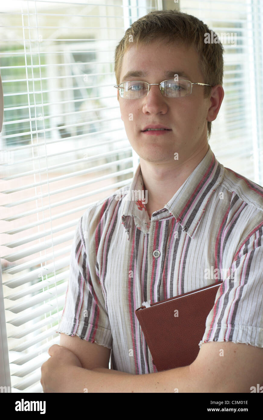 Serious young man with note book stands near window Stock Photo - Alamy