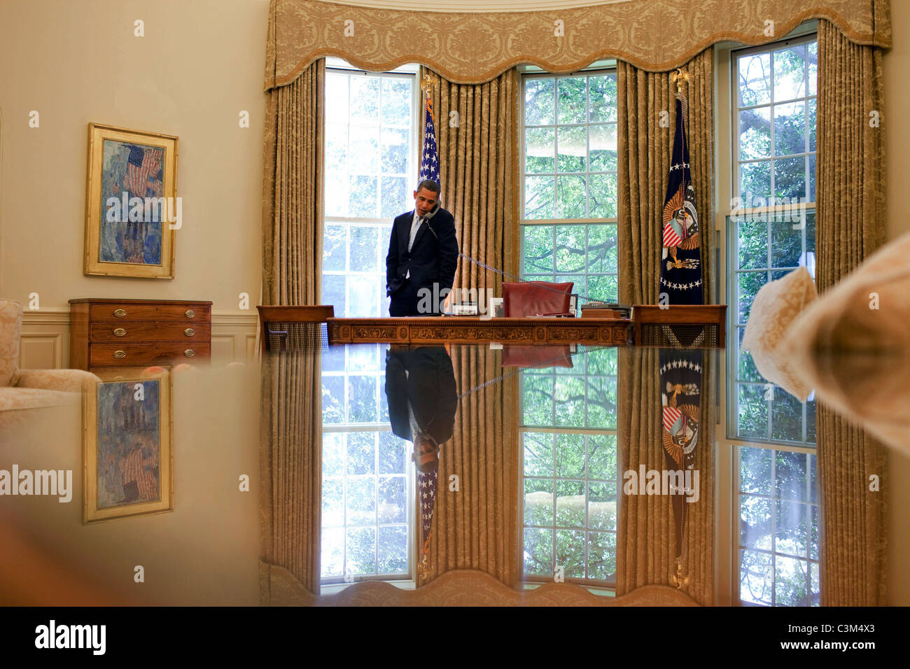President Barack Obama standing in the Oval Office during a phone call ...