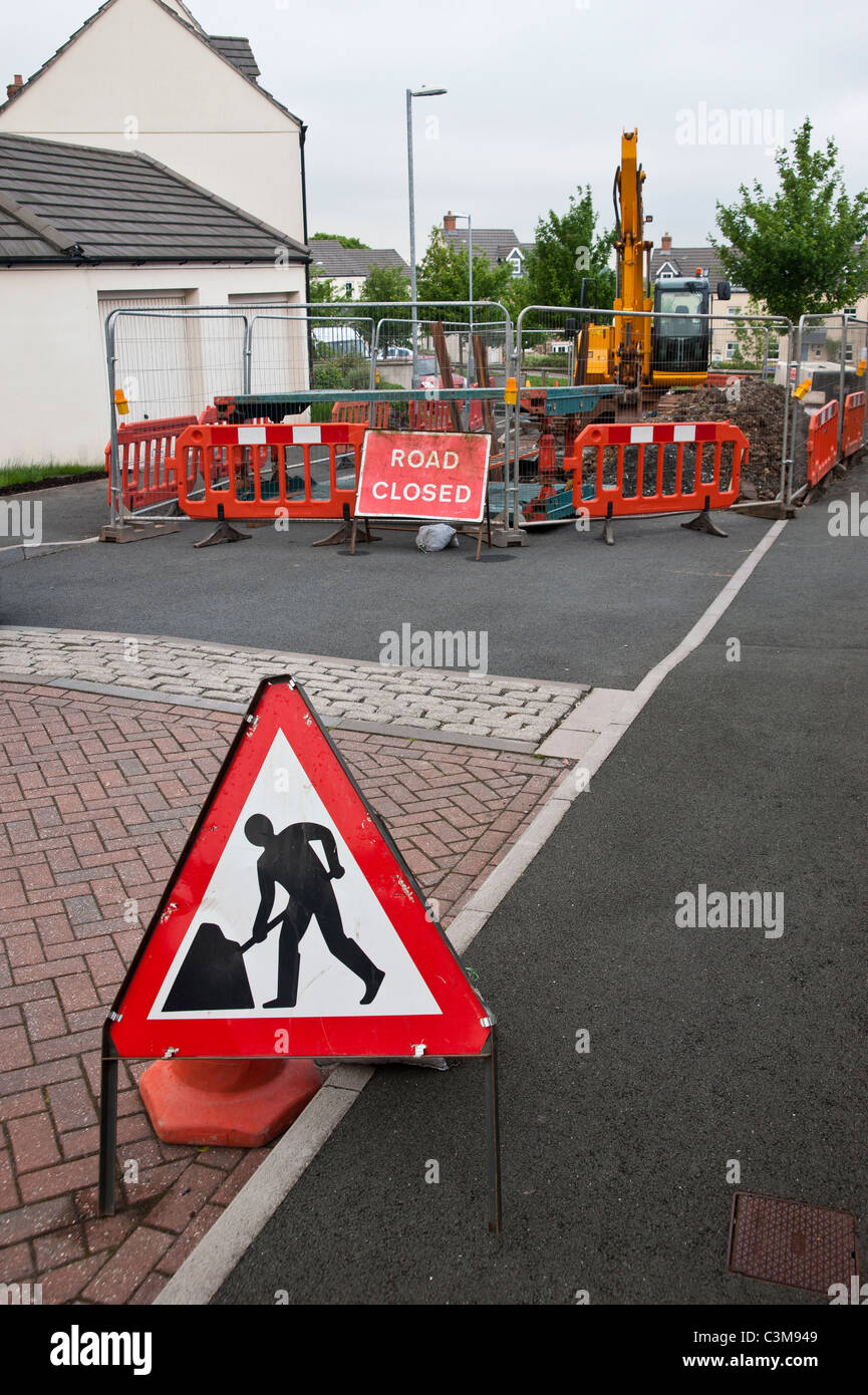 A men at work road sign near a section of urban road closed for ...