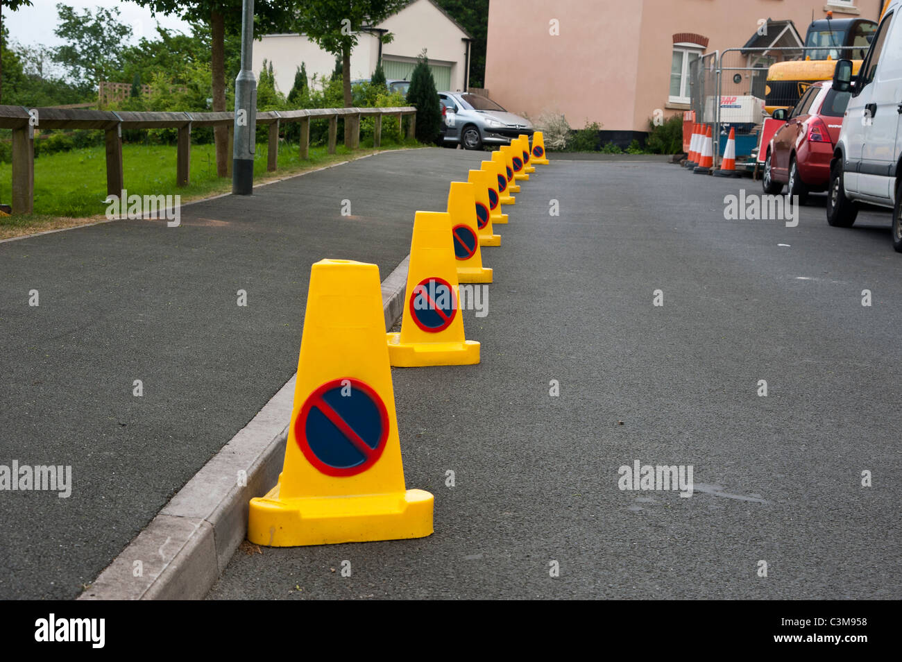 A row of yellow plastic traffic cones indicating a no-parking section ...
