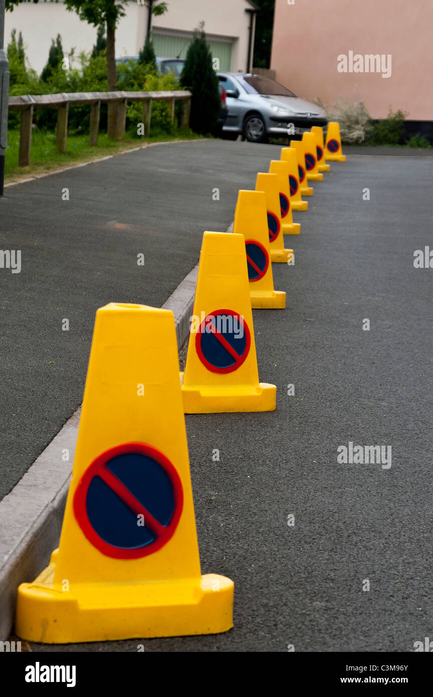 A row of yellow plastic traffic cones indicating a no-parking section ...