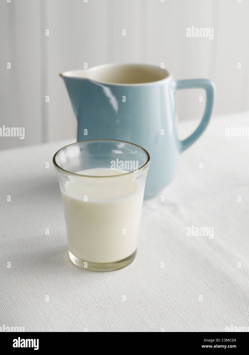 Glas of milk and pitcher on table Stock Photo - Alamy