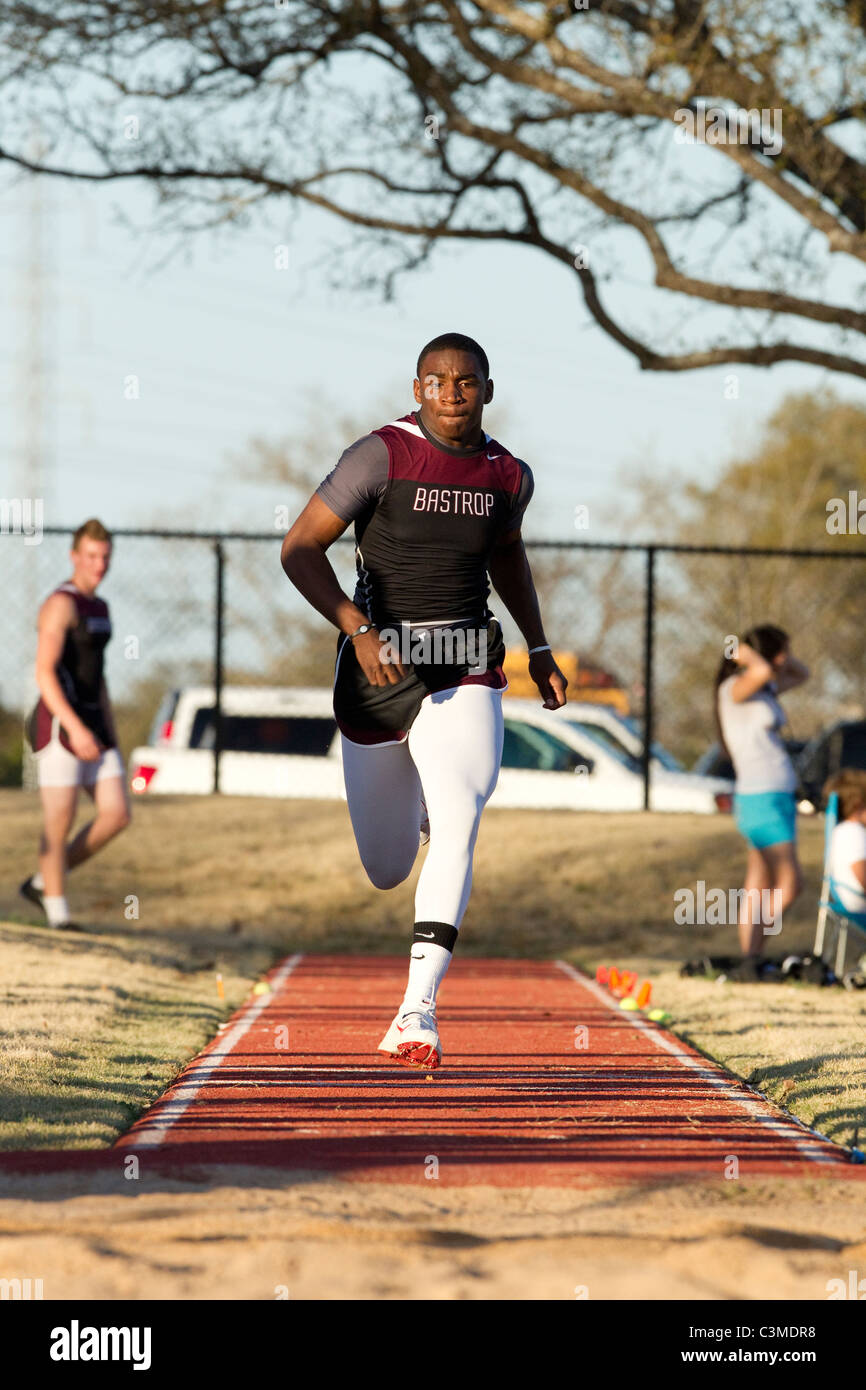 Male African-American high school age athlete runs during a long-jump ...
