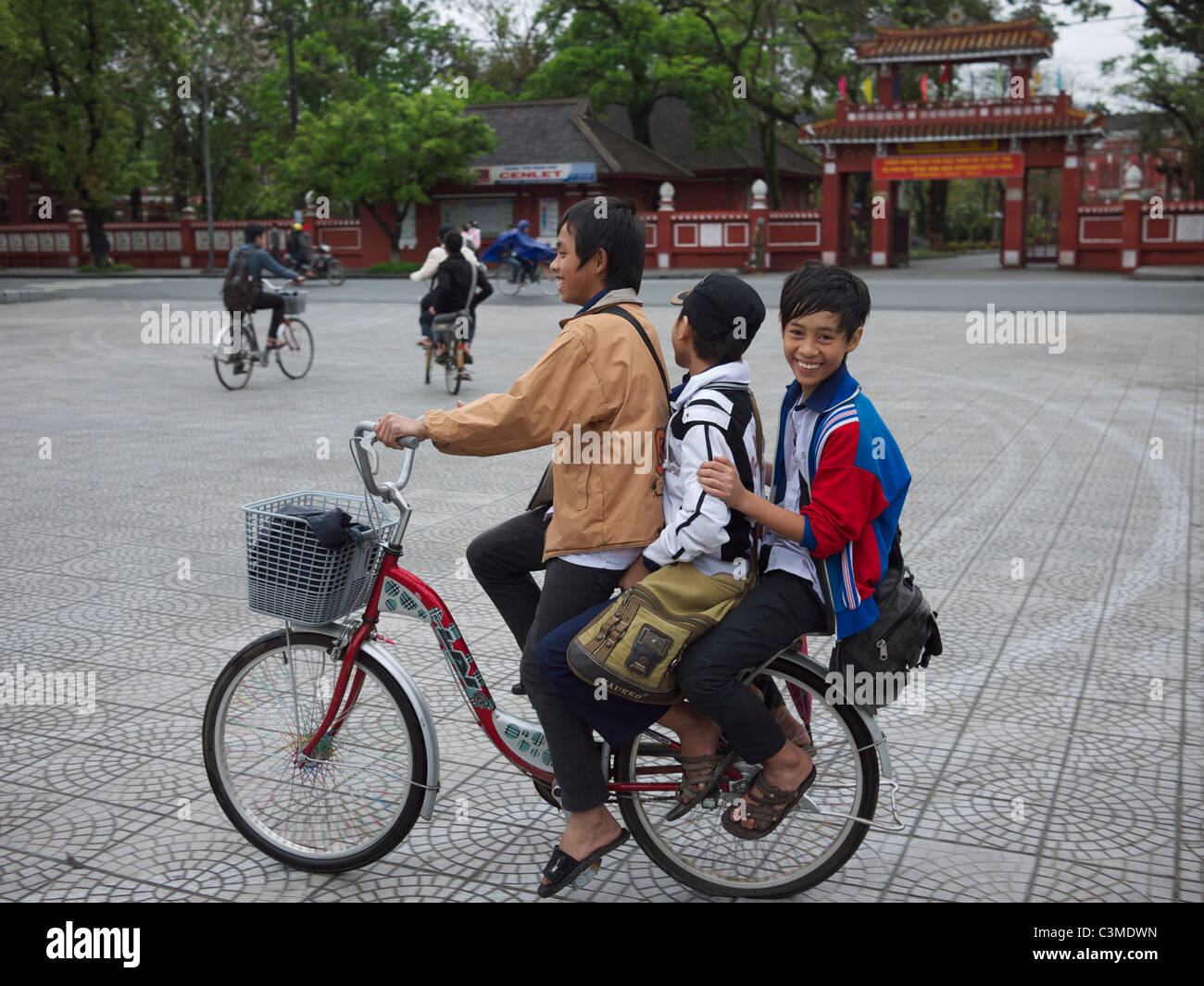 three 3 school children on one bicycle lingering in the park on their ...