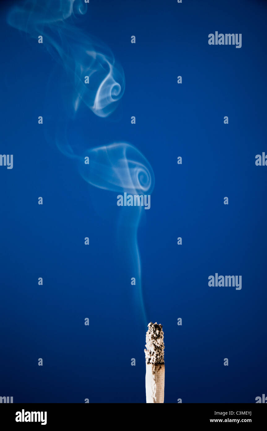Smoke of cigarette against blue background Stock Photo - Alamy