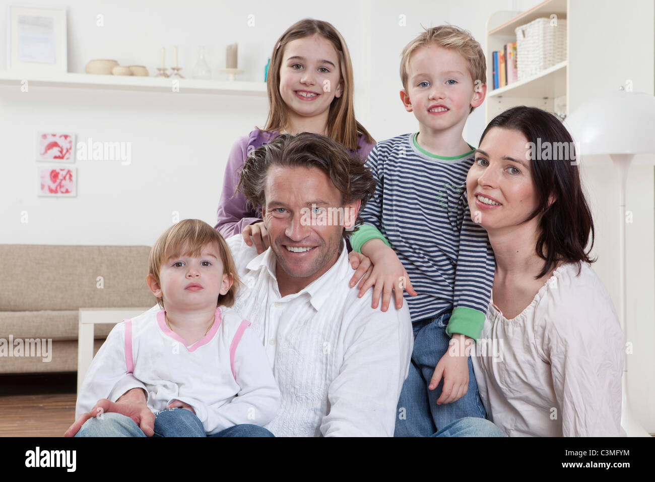 Germany, Bavaria, Munich, Family sitting on floor, smiling, portrait ...