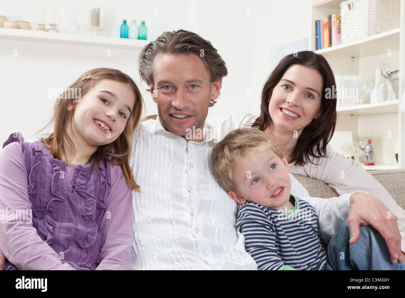 Germany, Bavaria, Munich, Family sitting on couch, smiling Stock Photo ...