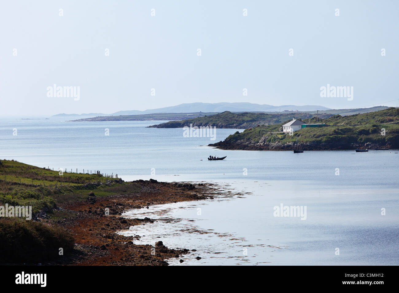 Ireland, County Galway, Connemara, View of boat in river with mountains ...