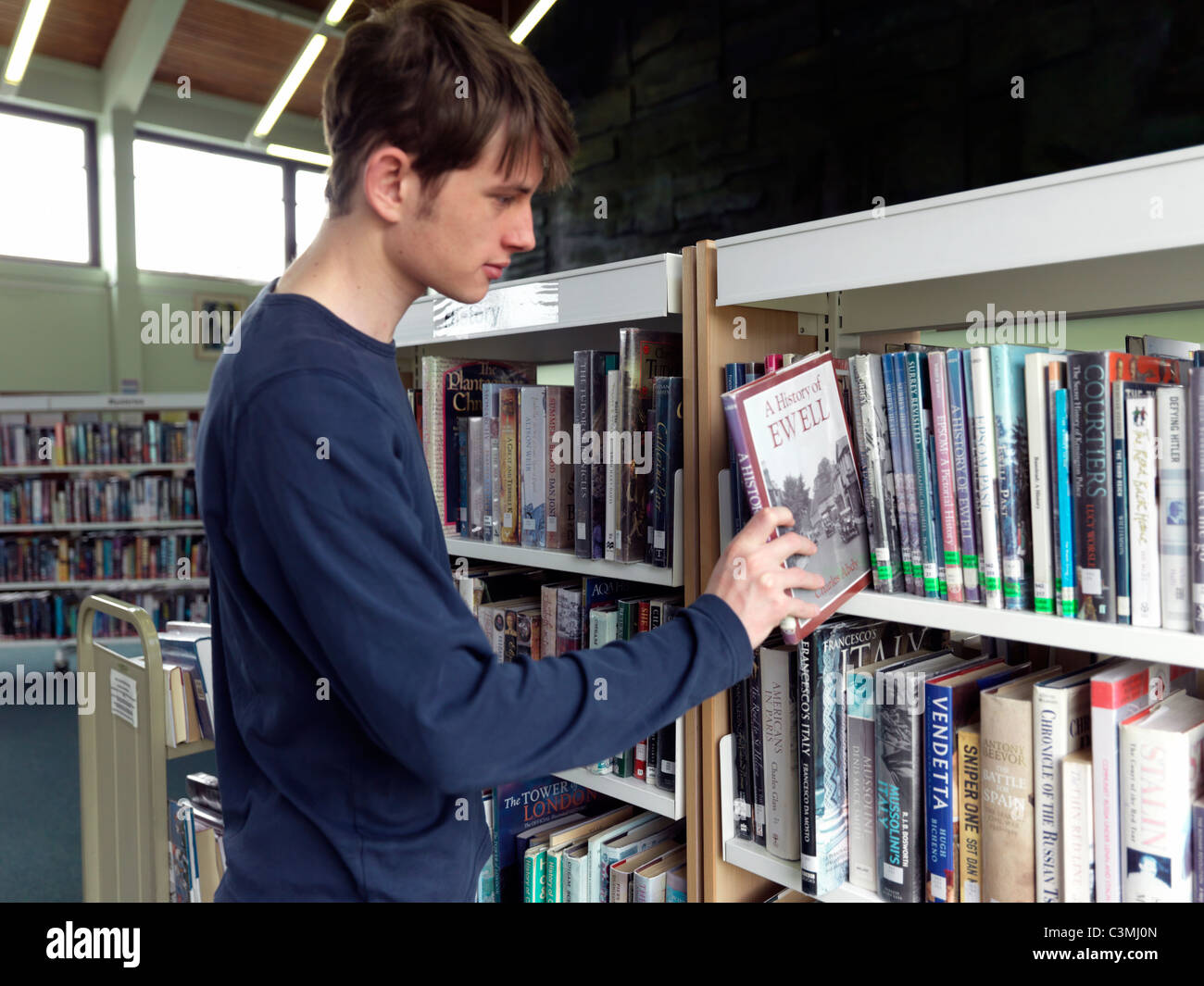 Teenage Boy Standing In A Library Looking At A Book Stock Photo - Alamy