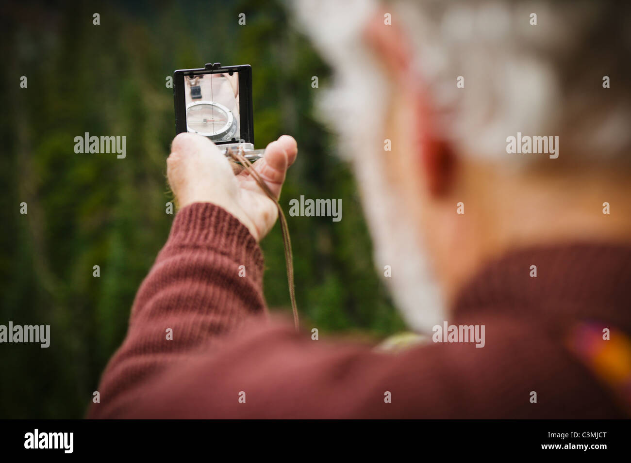 A view looking over a man's shoulder as he sites a compass reading ...