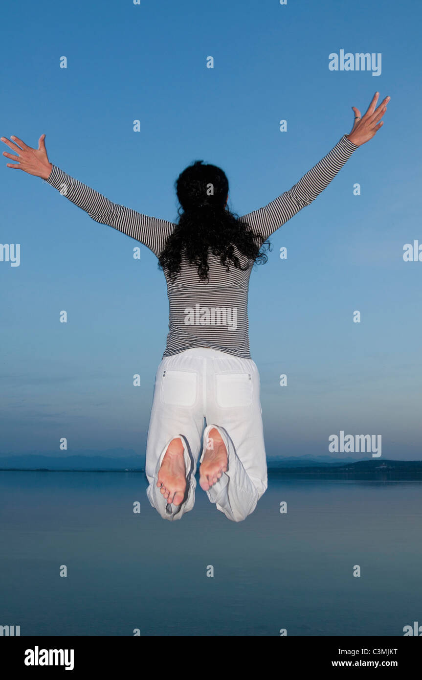 Mid adult woman jumping with arms up Stock Photo - Alamy