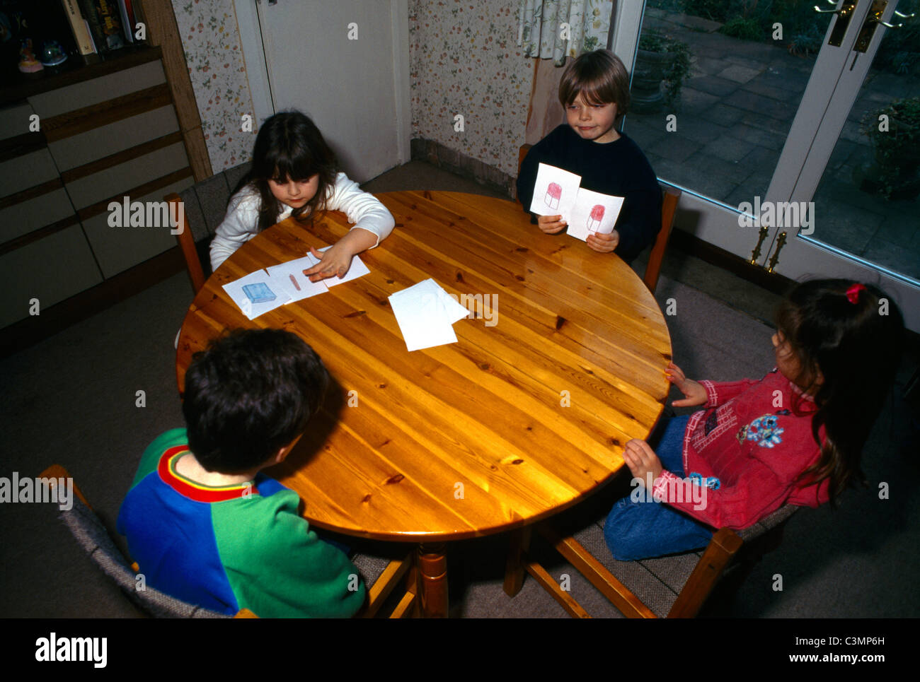 Young Children Playing Game Of Cards Around The Table Stock Photo - Alamy