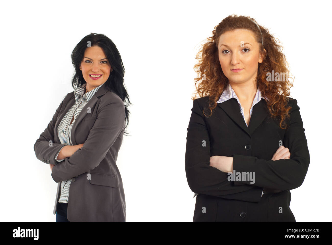 Attractive smiling two business women standing with arms folded ...
