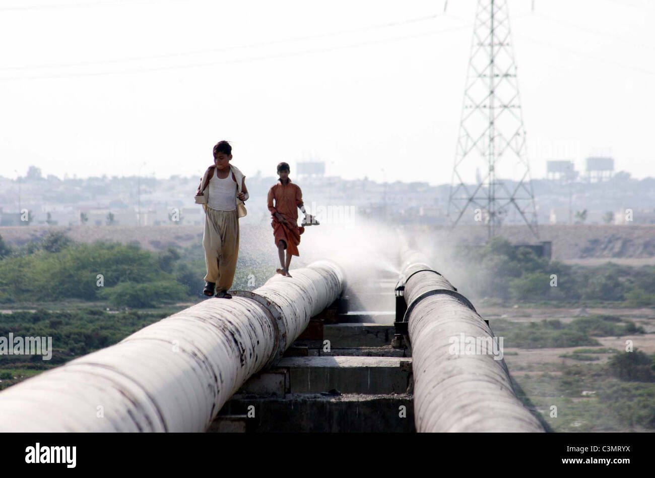 Two children pass through a broken drinking water pipeline at Korangi ...
