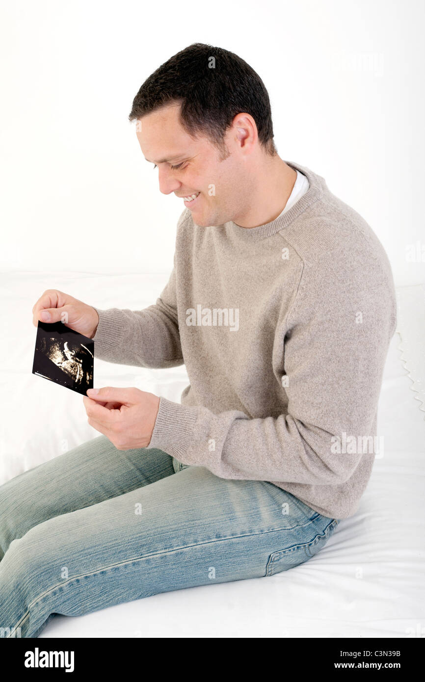 Dad to be looking at ultrasound scan of his baby Stock Photo - Alamy