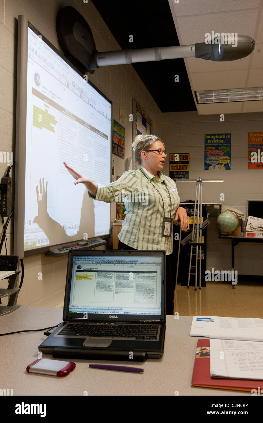 Female Anglo teacher uses laptop computer to display lesson on screen ...