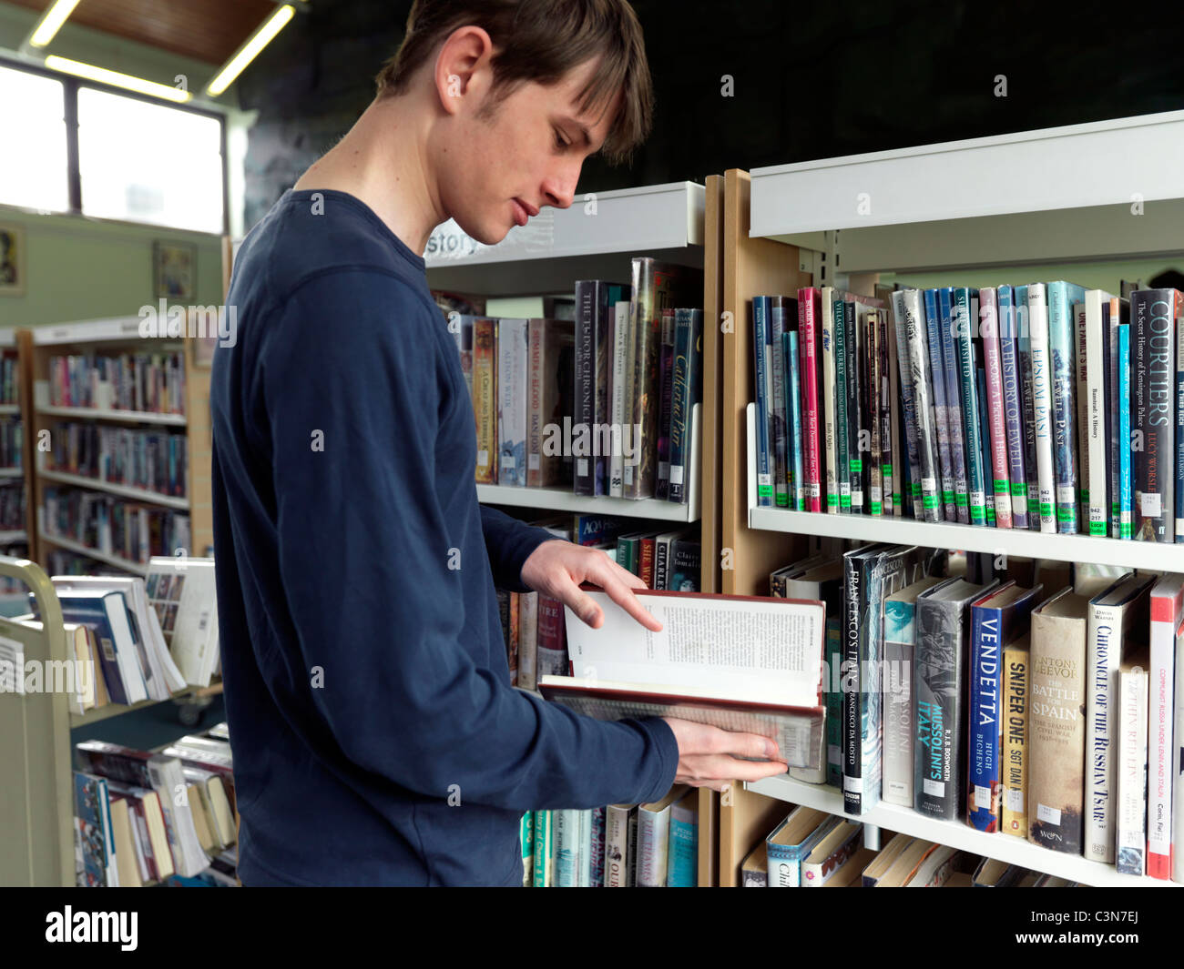 Teenage Boy Standing In A Library Looking At A Book Stock Photo - Alamy