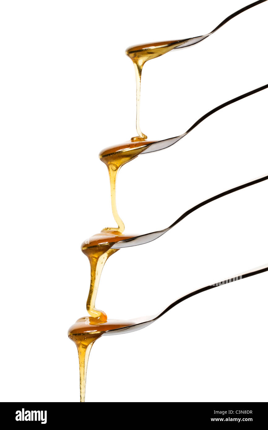 honey falling over four spoons on white background Stock Photo - Alamy