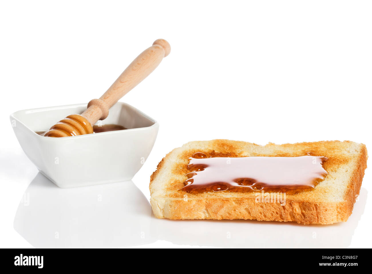toast with honey an a honey jar with a honey dipper on white background ...