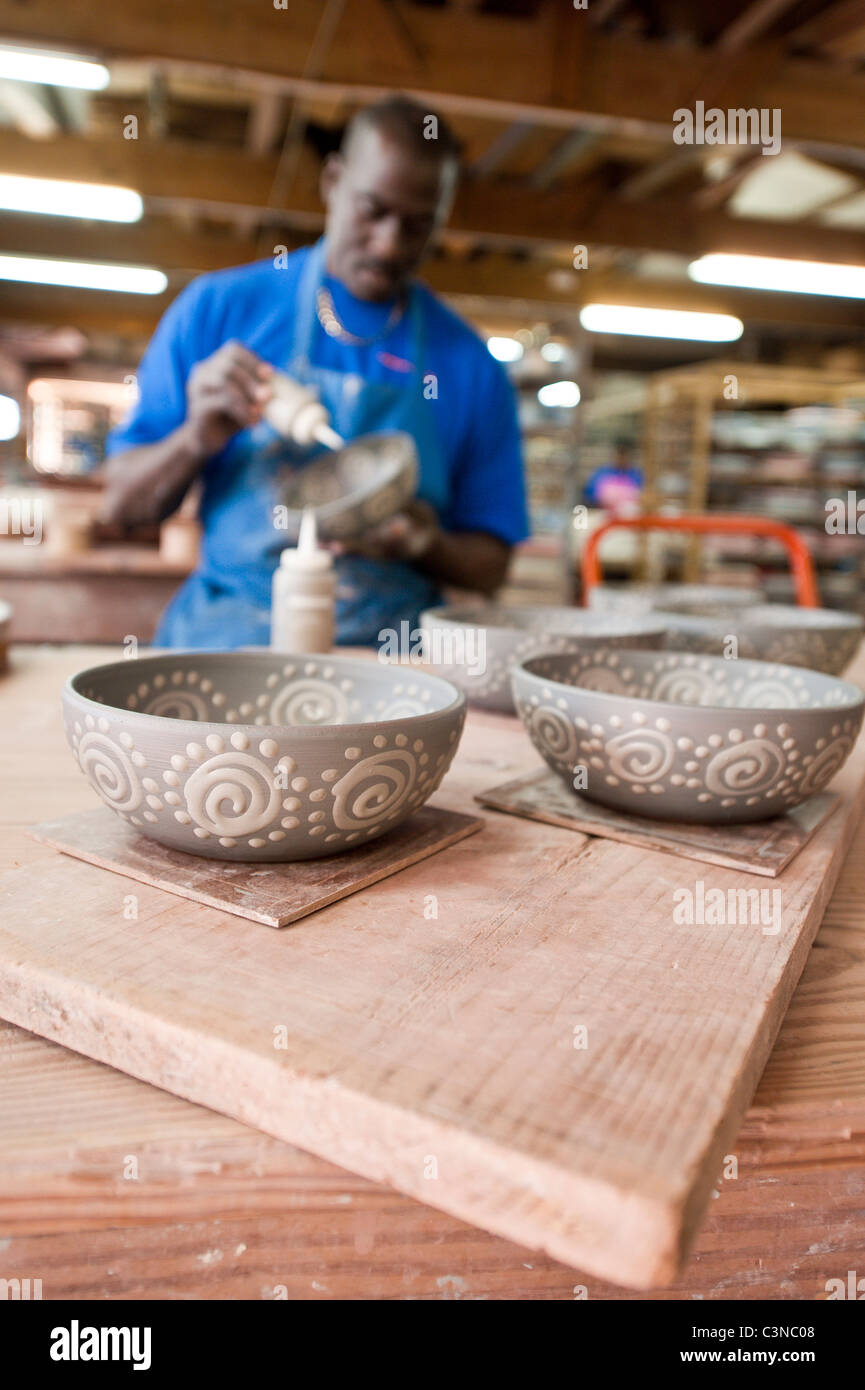 Potter decorates clay pottery at Earthworks pottery workshop studio ...