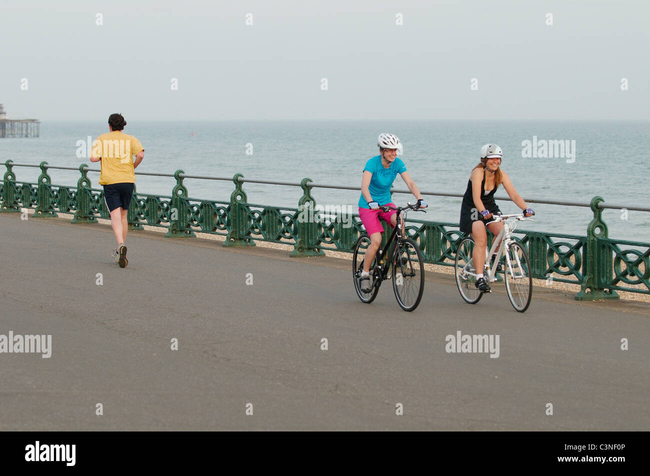 Two women riding bikes along Brighton seafront. Brighton,UK Stock Photo ...