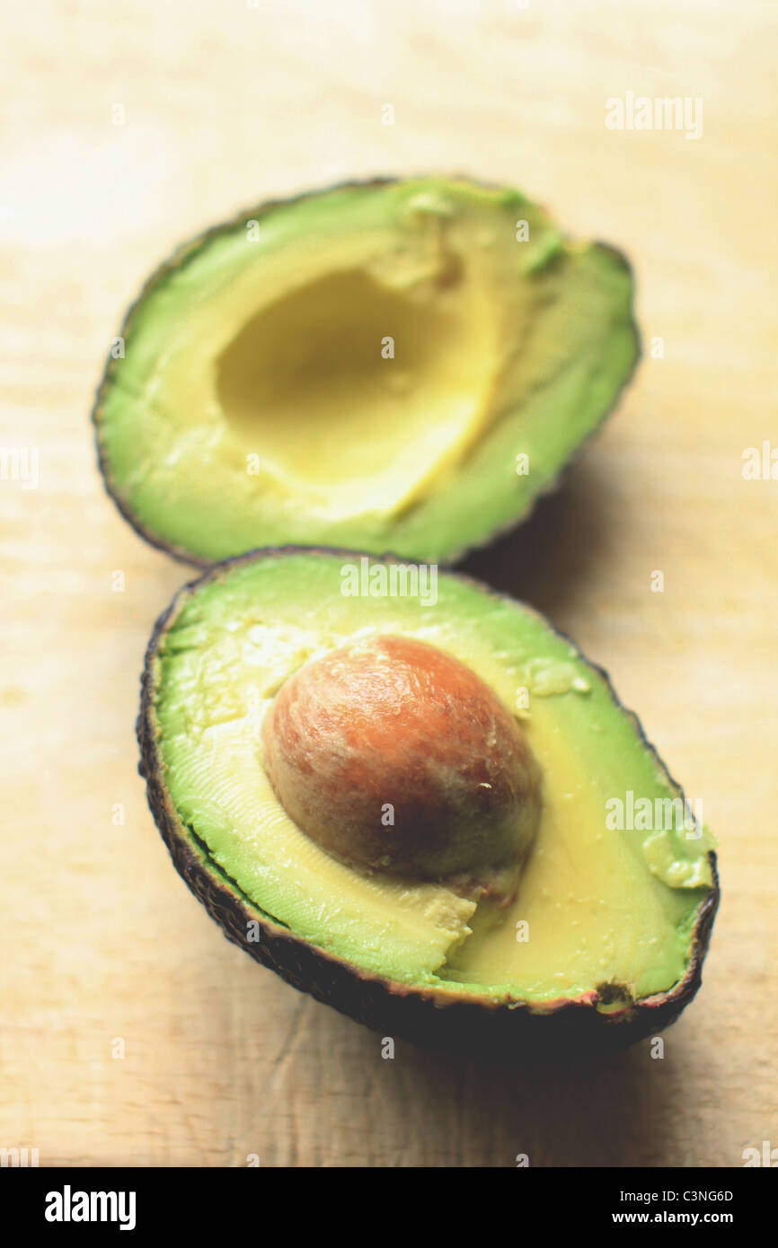Avocado cut open on a pale wood background Stock Photo - Alamy