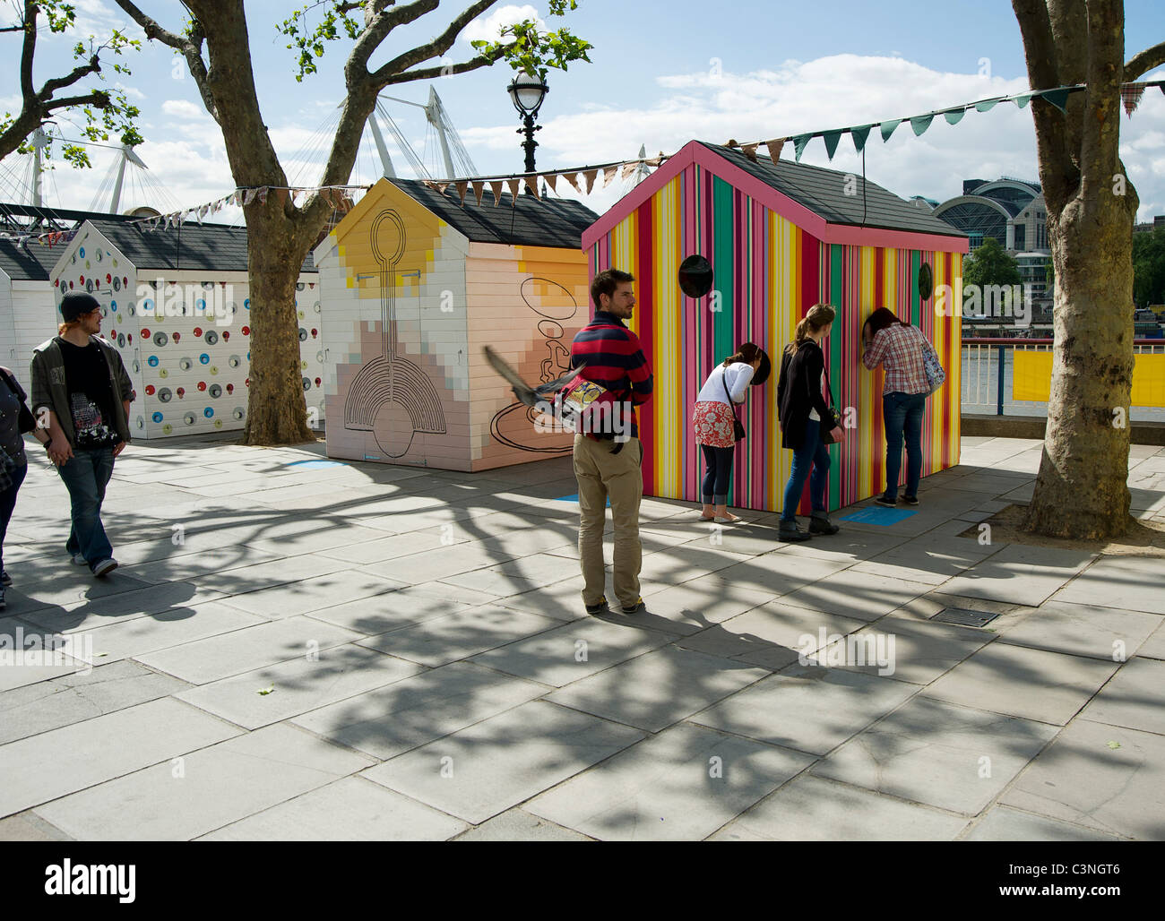 People looking into colourful beach huts on London's Southbank Stock ...