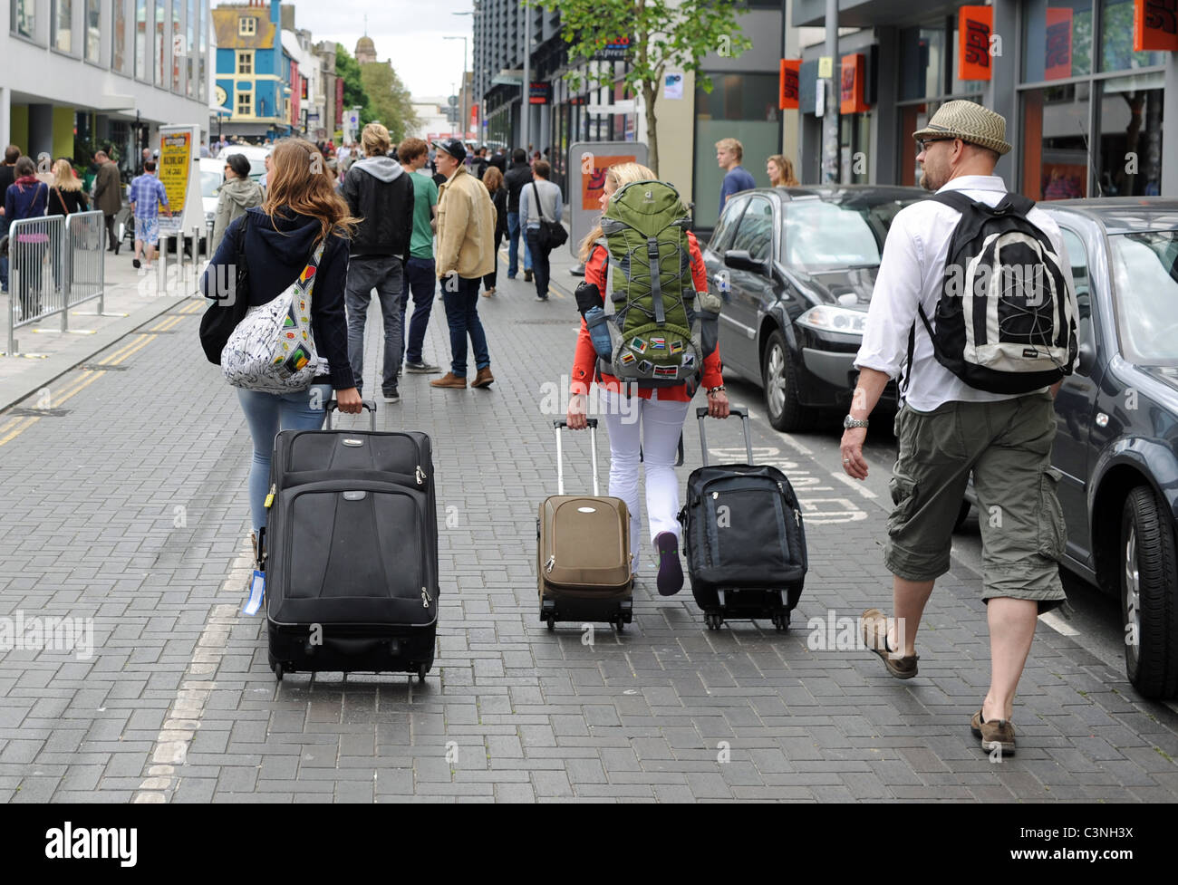 Travellers with pull luggage walking through Brighton city centre Uk ...
