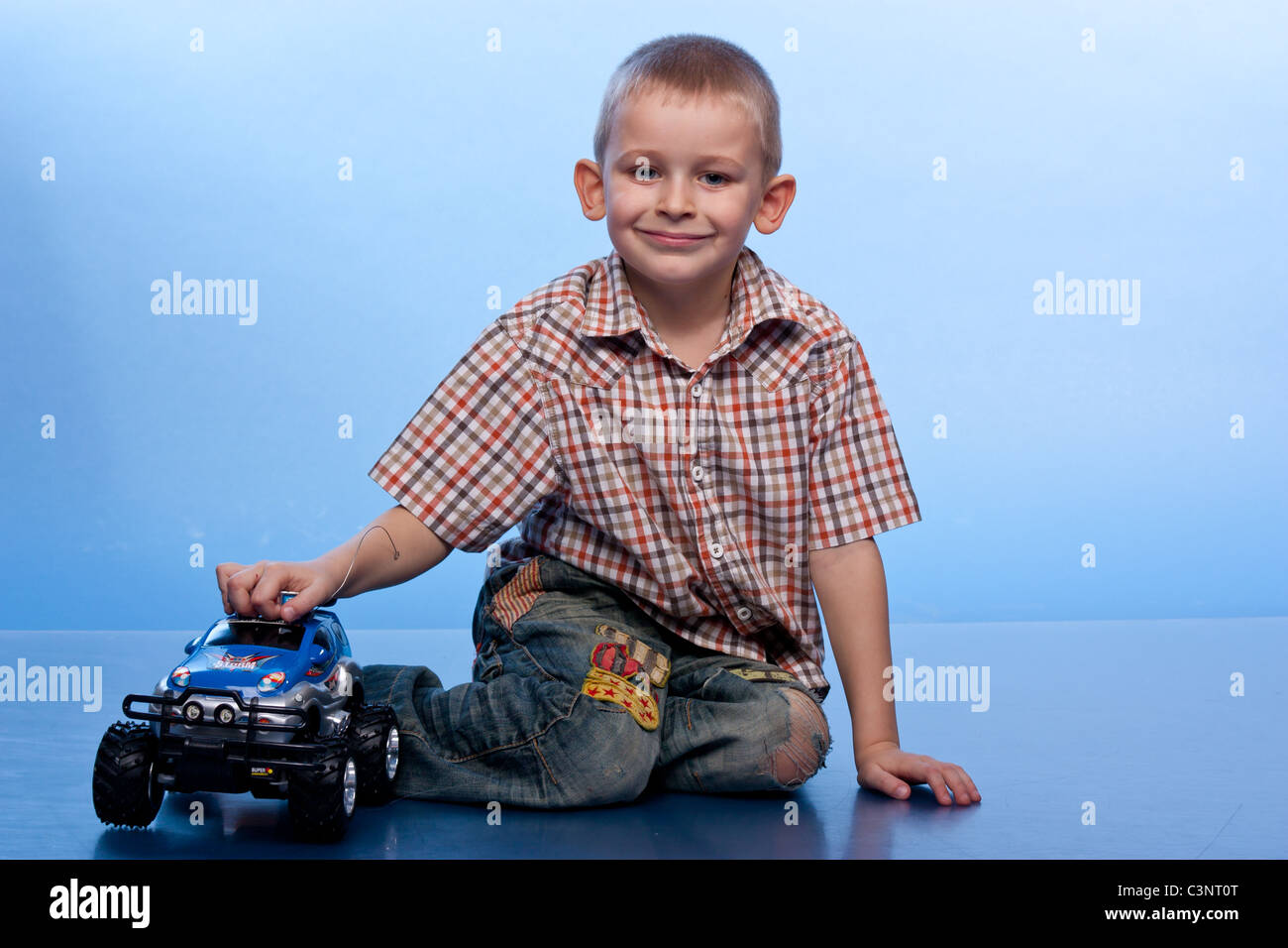 Happy boy playing with car against blue brackground Stock Photo - Alamy