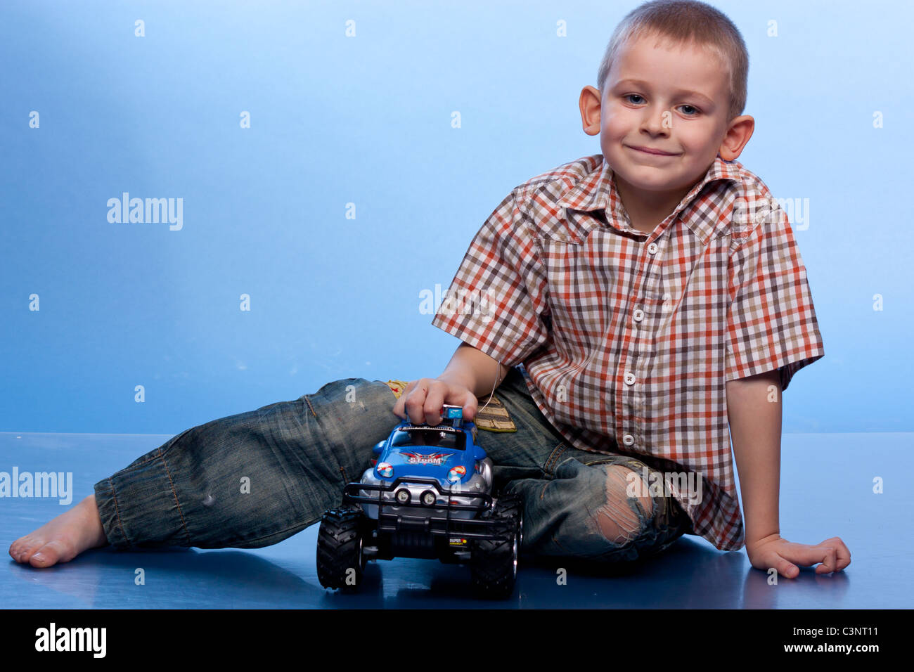 Happy boy playing with car against blue brackground Stock Photo - Alamy