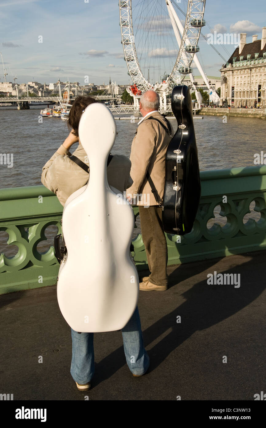 Cellists carrying cello cases on their backs looking at the London Eye ...