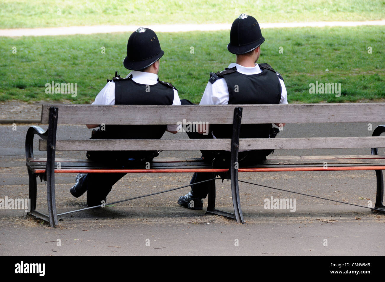 Bobbies sitting on a bench, two Metropolitan police officers watching ...