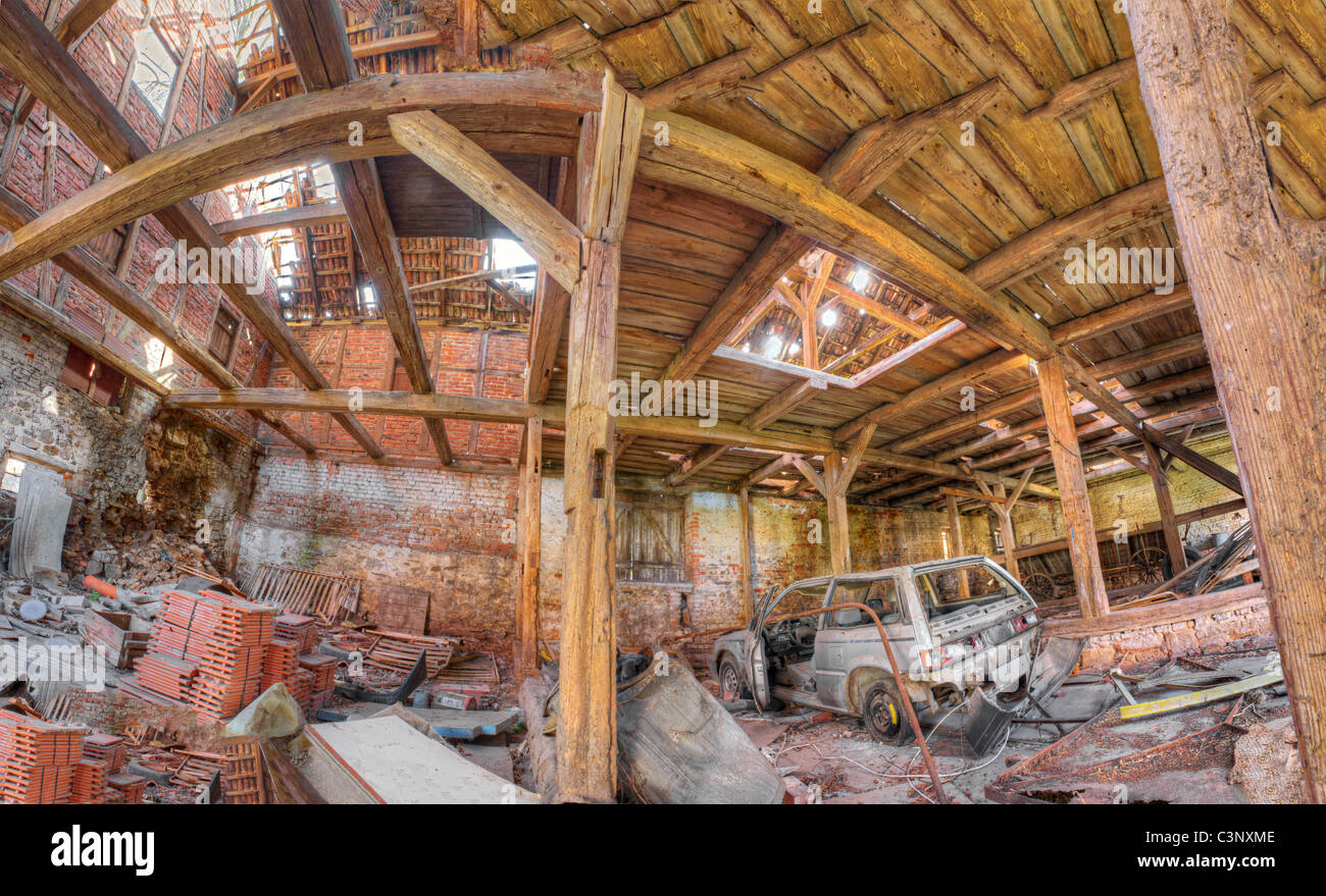 Panorama of a messy, wrecked, abandoned barn interior with trash piling ...