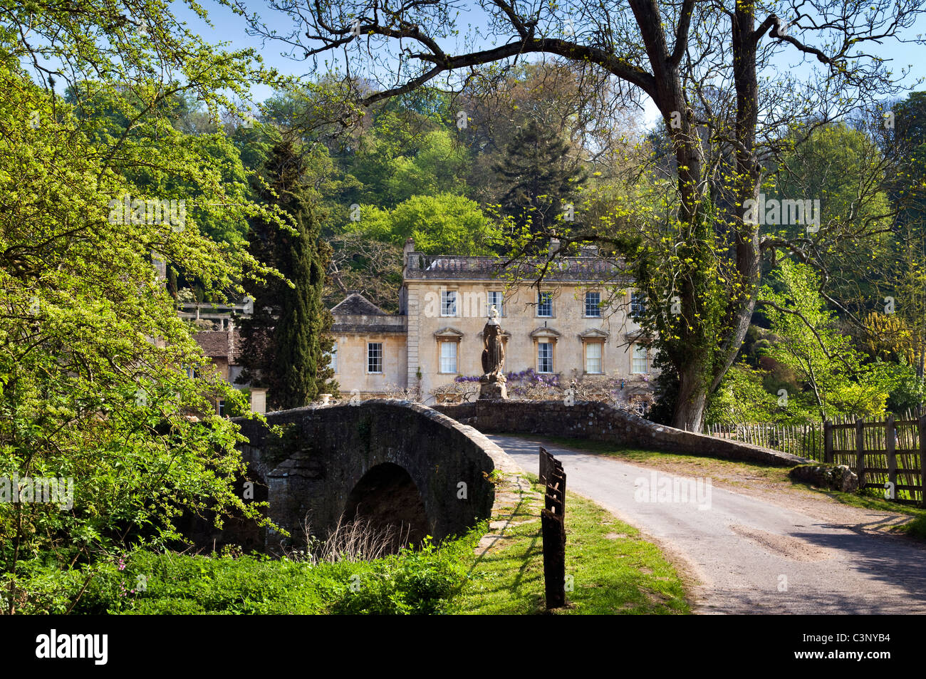 Picturesque scene at Iford of single track road, bridge and Iford manor ...
