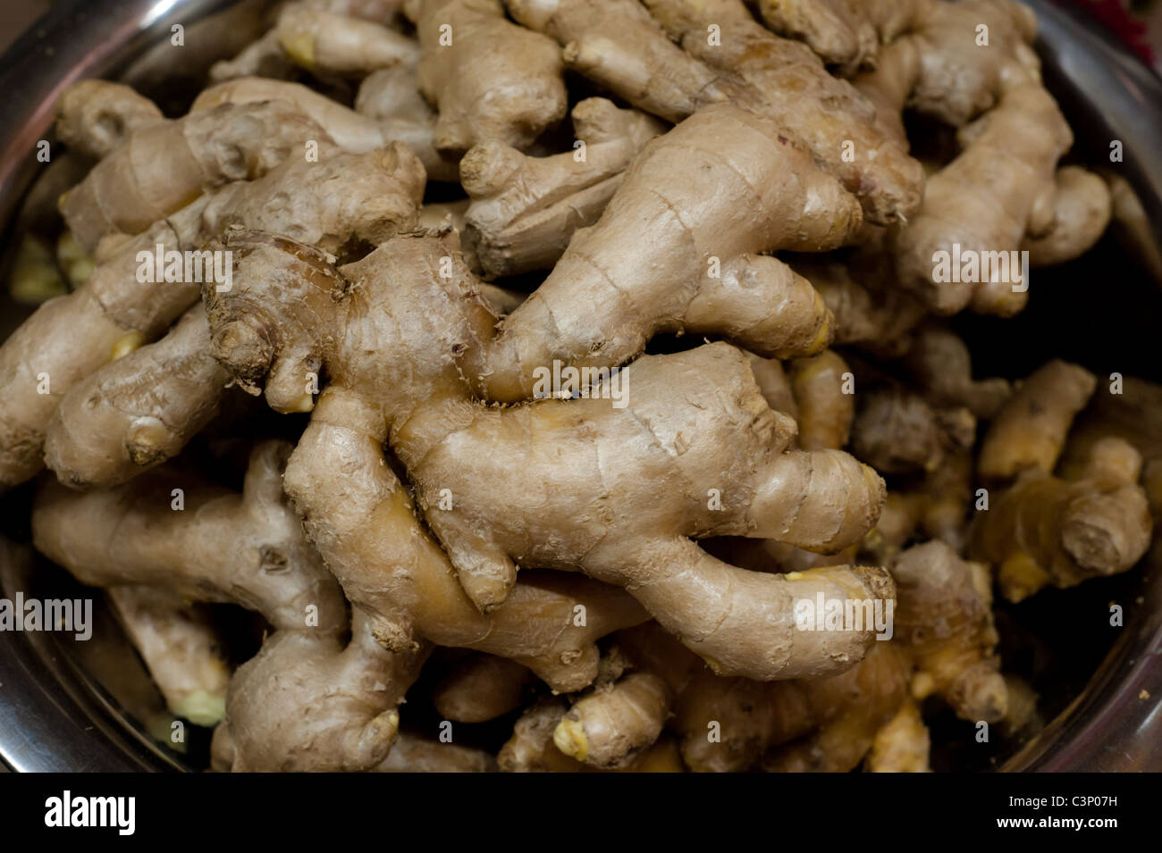 A pile of ginger root fills a bowl in a spice and dry goods store in ...