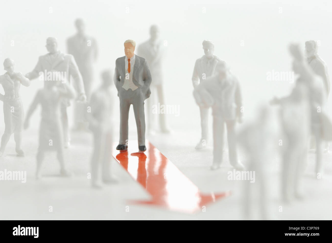 Businessman figurine standing on arrow sign Stock Photo - Alamy