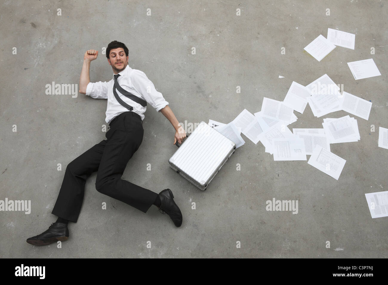 Business man carrying suitcase, papers spilling out, elevated view ...