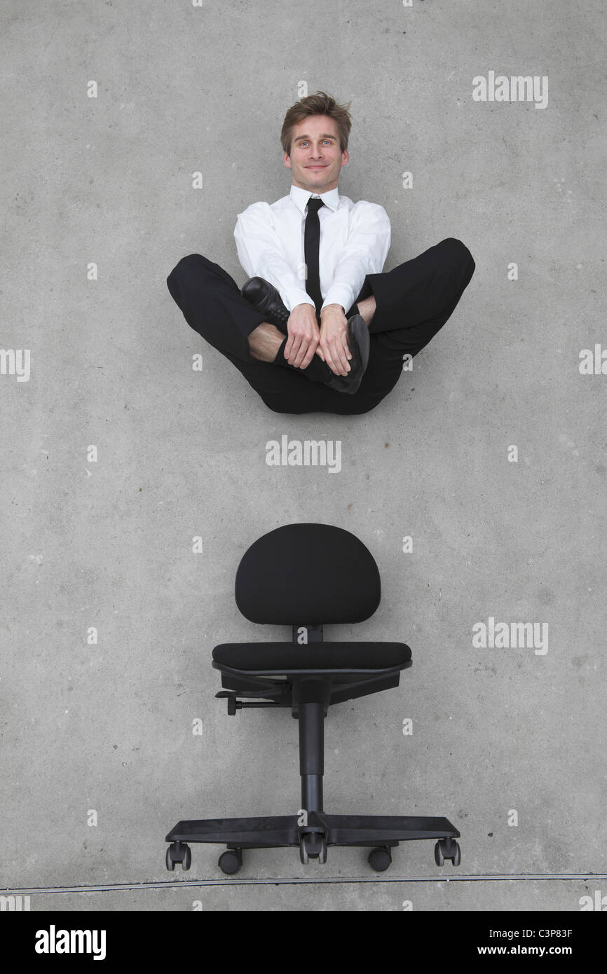 Businessman floating above chair, smiling, portrait, elevated view ...