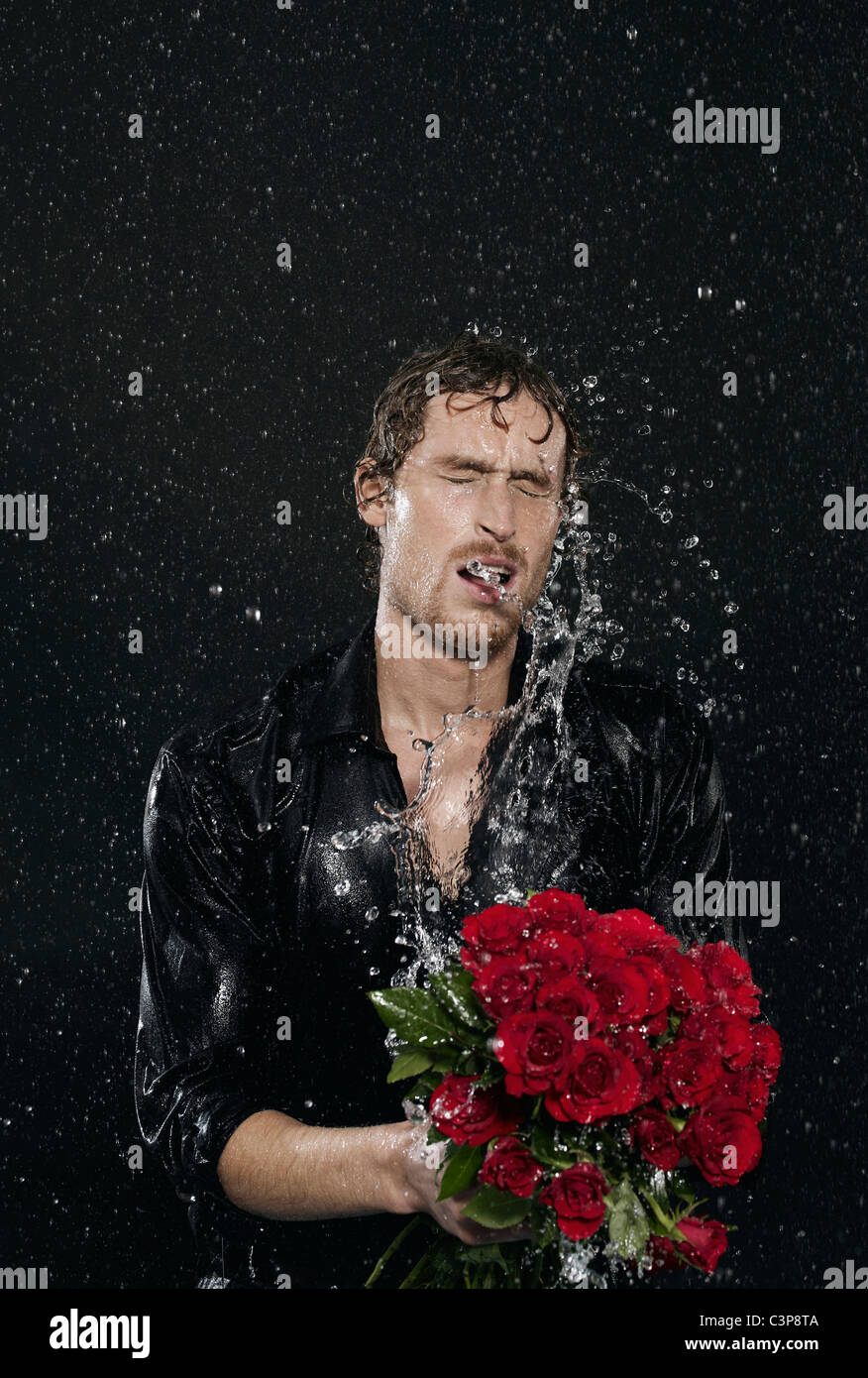 Man standing in rain, holding bunch of flowers, splashing water Stock ...