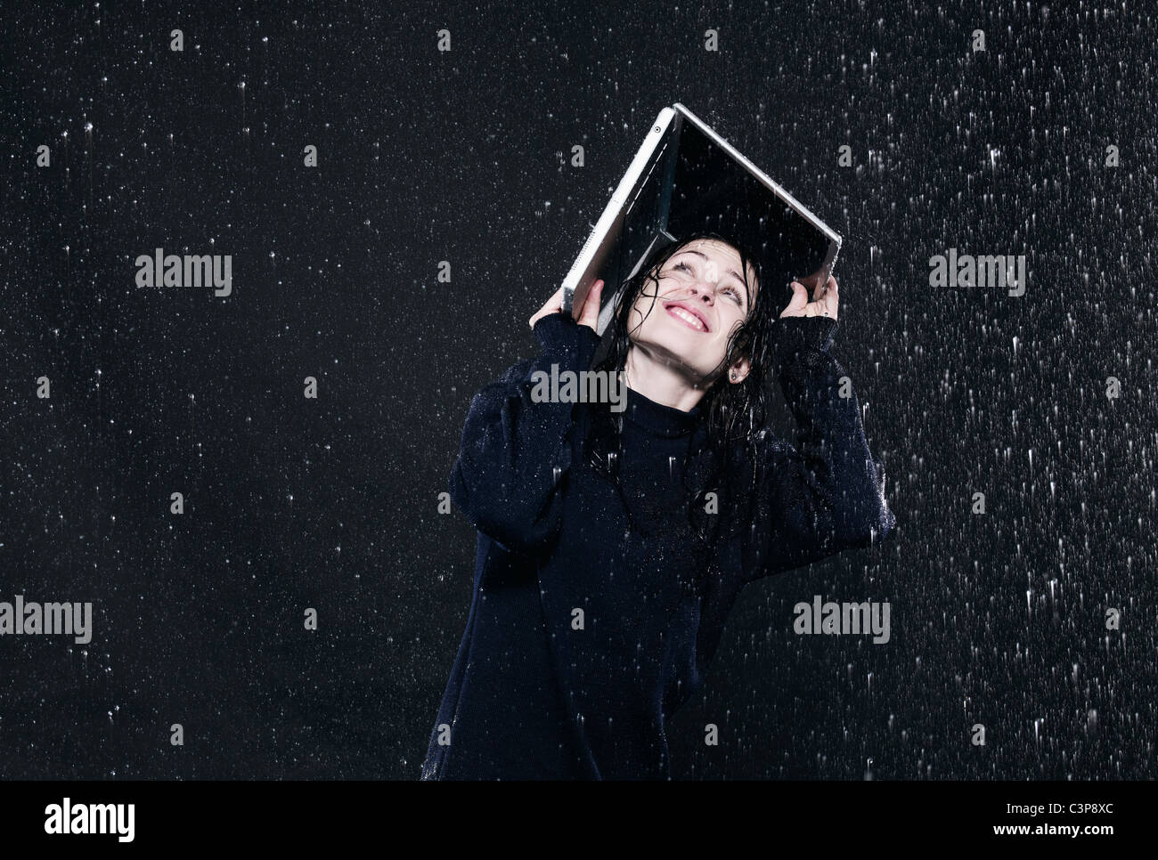 Woman sheltering from rain under laptop Stock Photo - Alamy