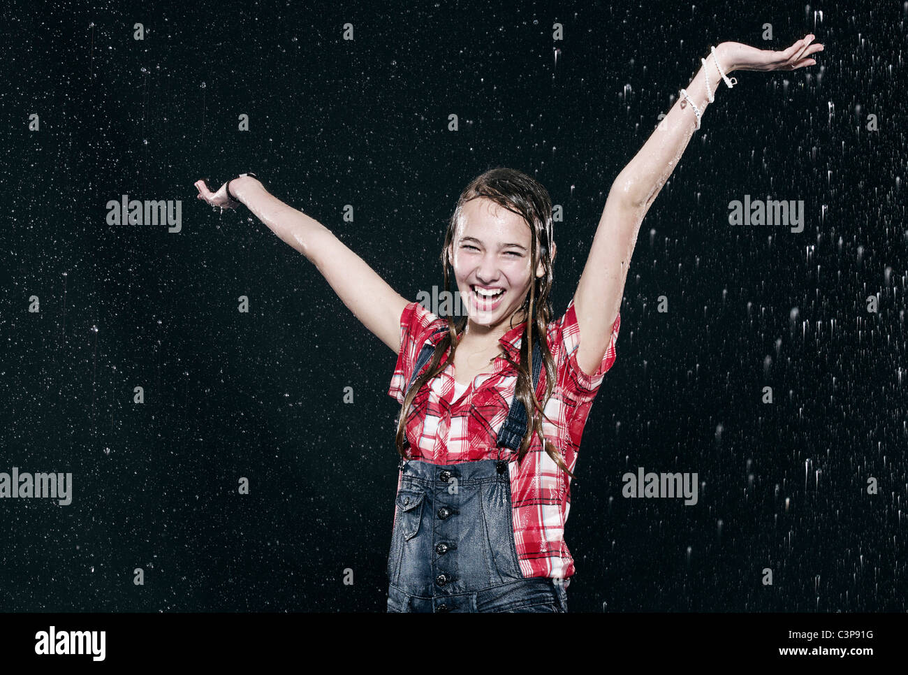 Girl standing in rain, arms up, smiling Stock Photo - Alamy