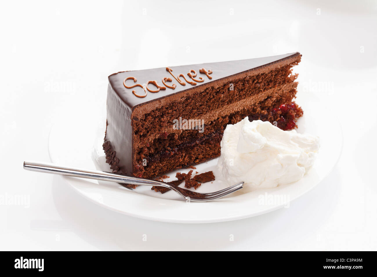 Slice of sacher cake with whipped cream in plate Stock Photo - Alamy