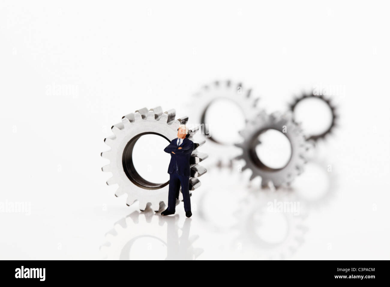 Manager figurine standing with cogwheels in background Stock Photo - Alamy